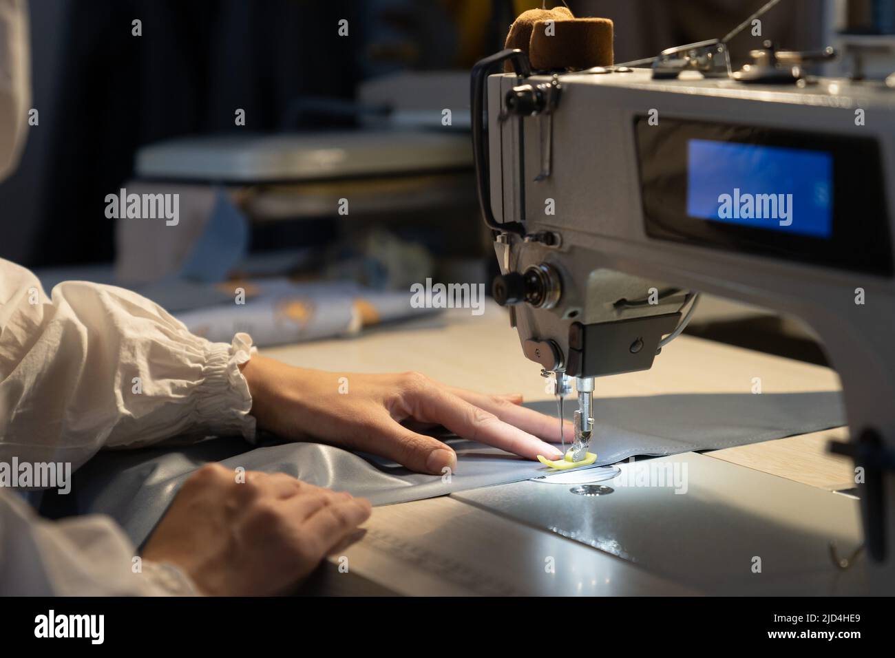 Closeup of female tailor work on sewing machine stitch fabric patterns ...