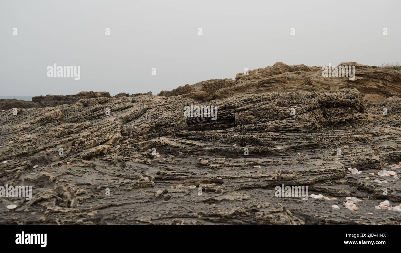 Volcanogenic rock slabs on the seashore. Natural rocky breakwater at ...