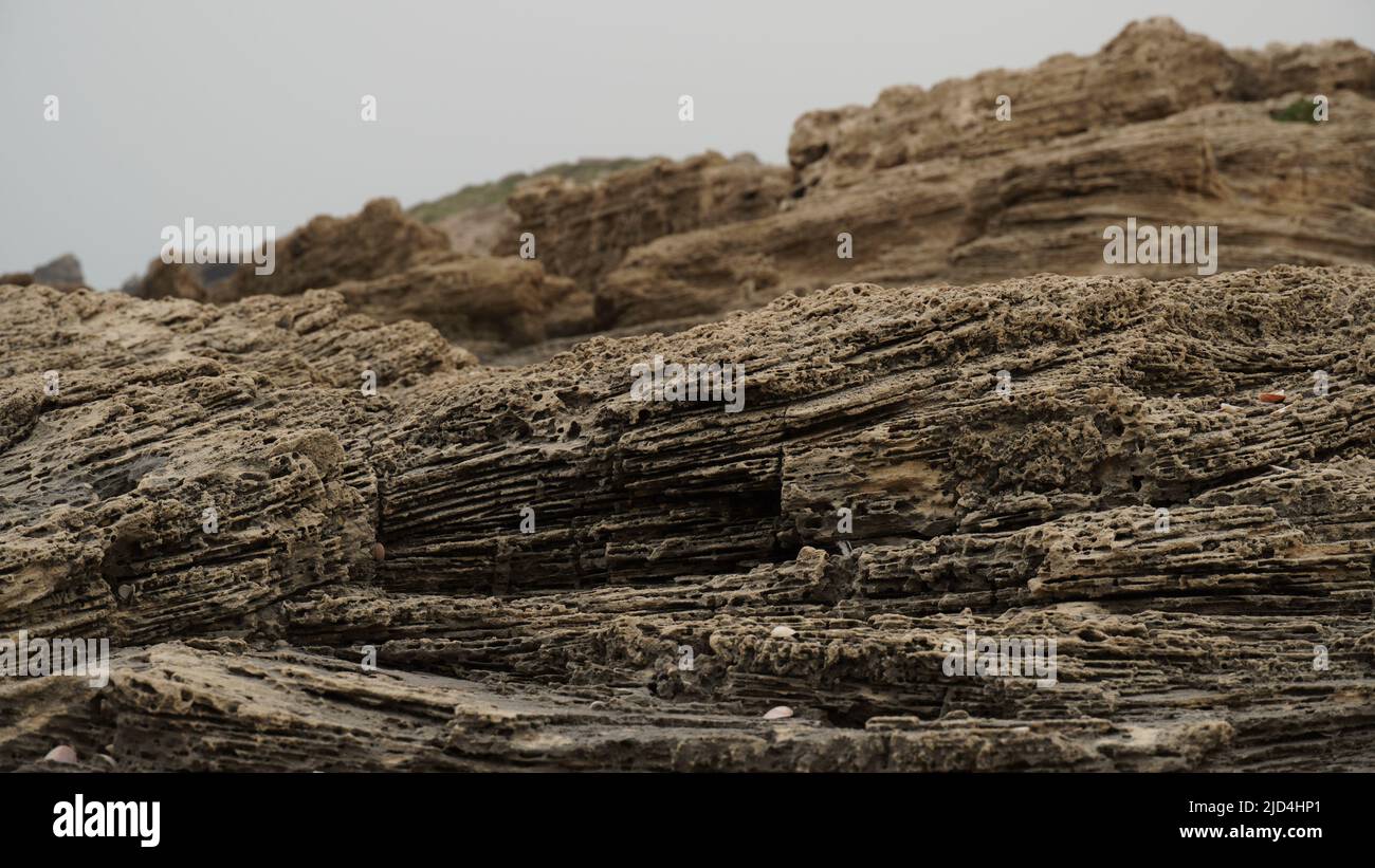 Volcanogenic rock slabs on the seashore. Natural rocky breakwater at ...