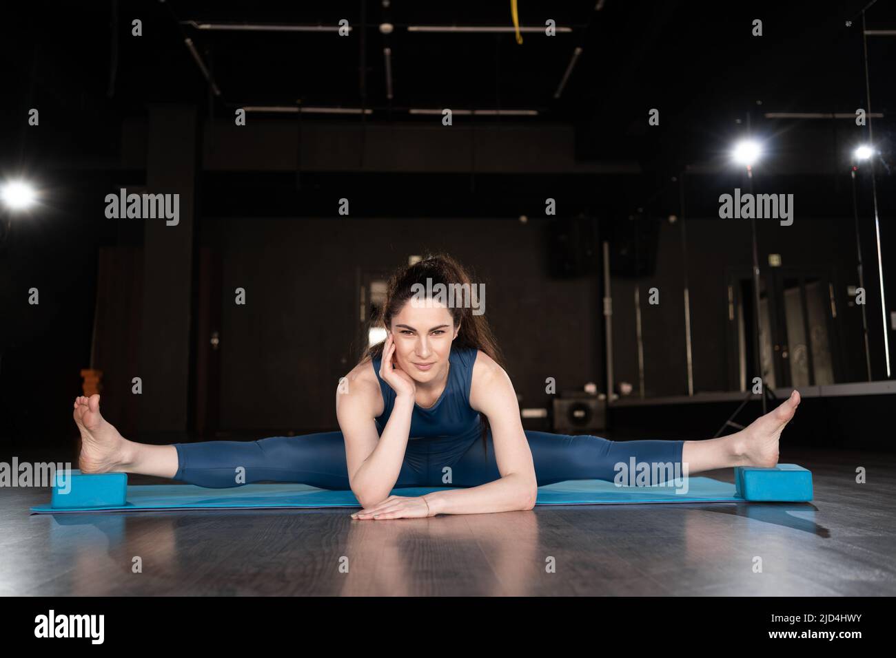 Young slim woman is doing some twine to stretch her legs. Joyful woman ...