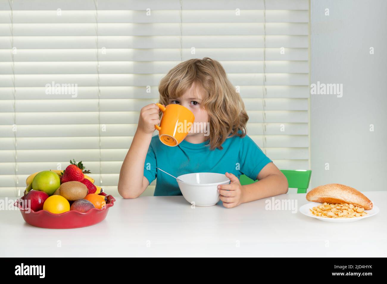 Kid boy eating healthy food vegetables. Breakfast with milk, fruits and ...