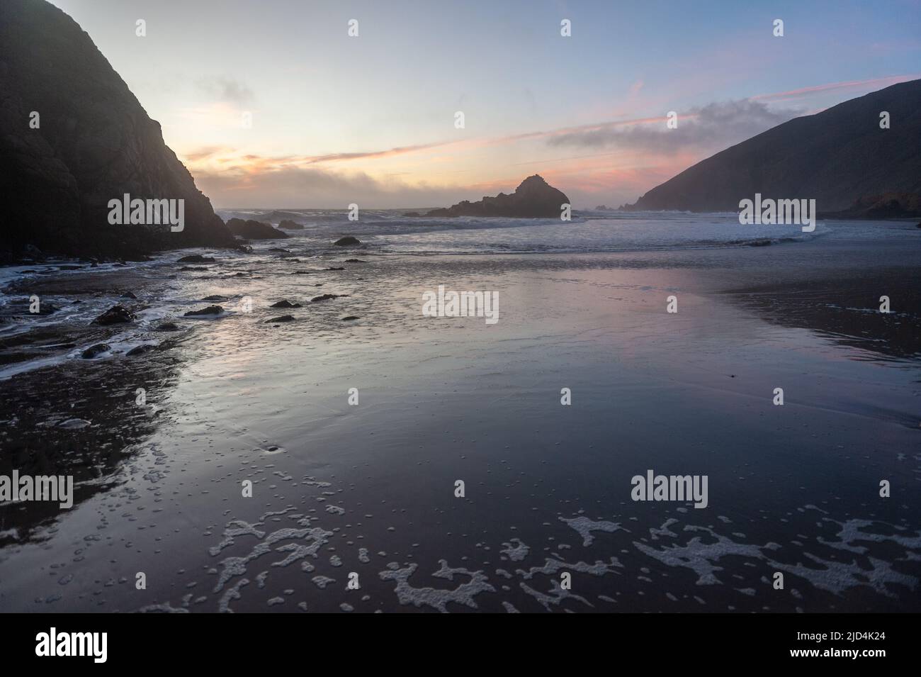 Receding ocean tides at Pfeiffer beach leaves a layer of water ...