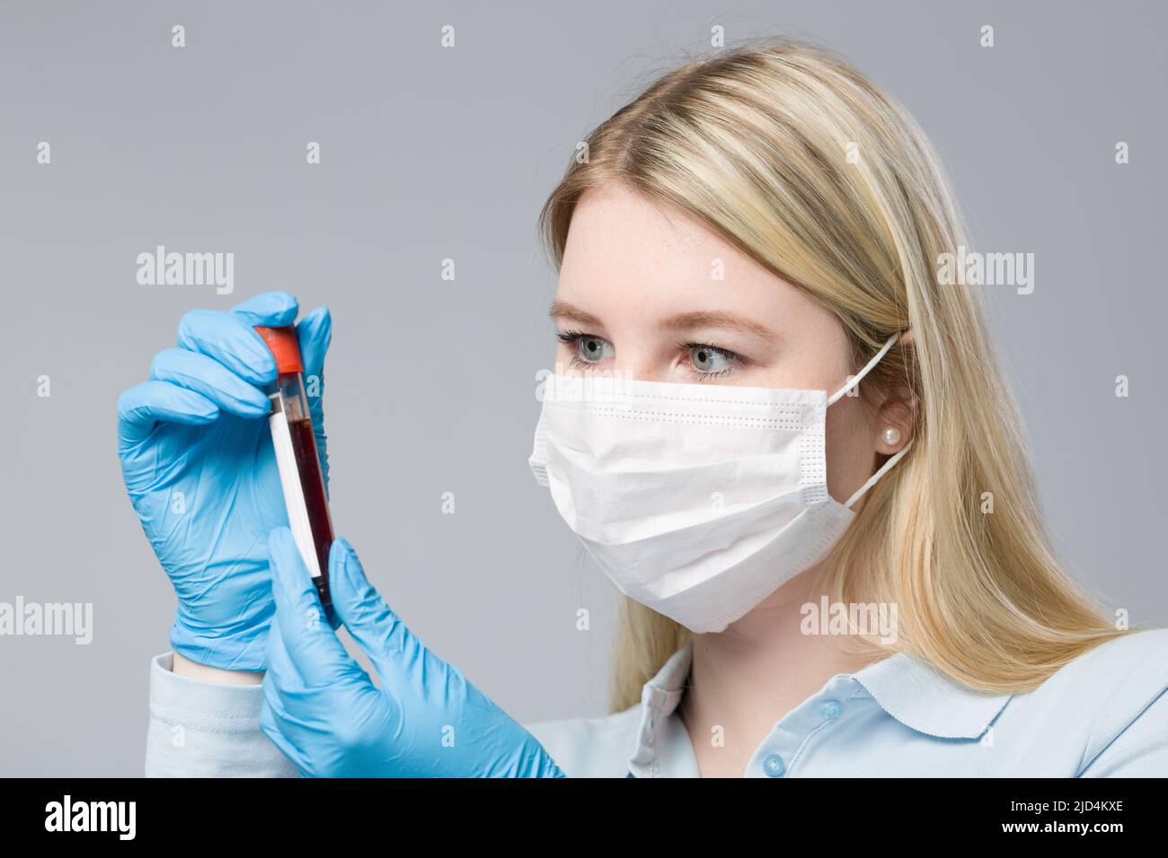 young woman with medical gloves and medical face mask handling a blood ...