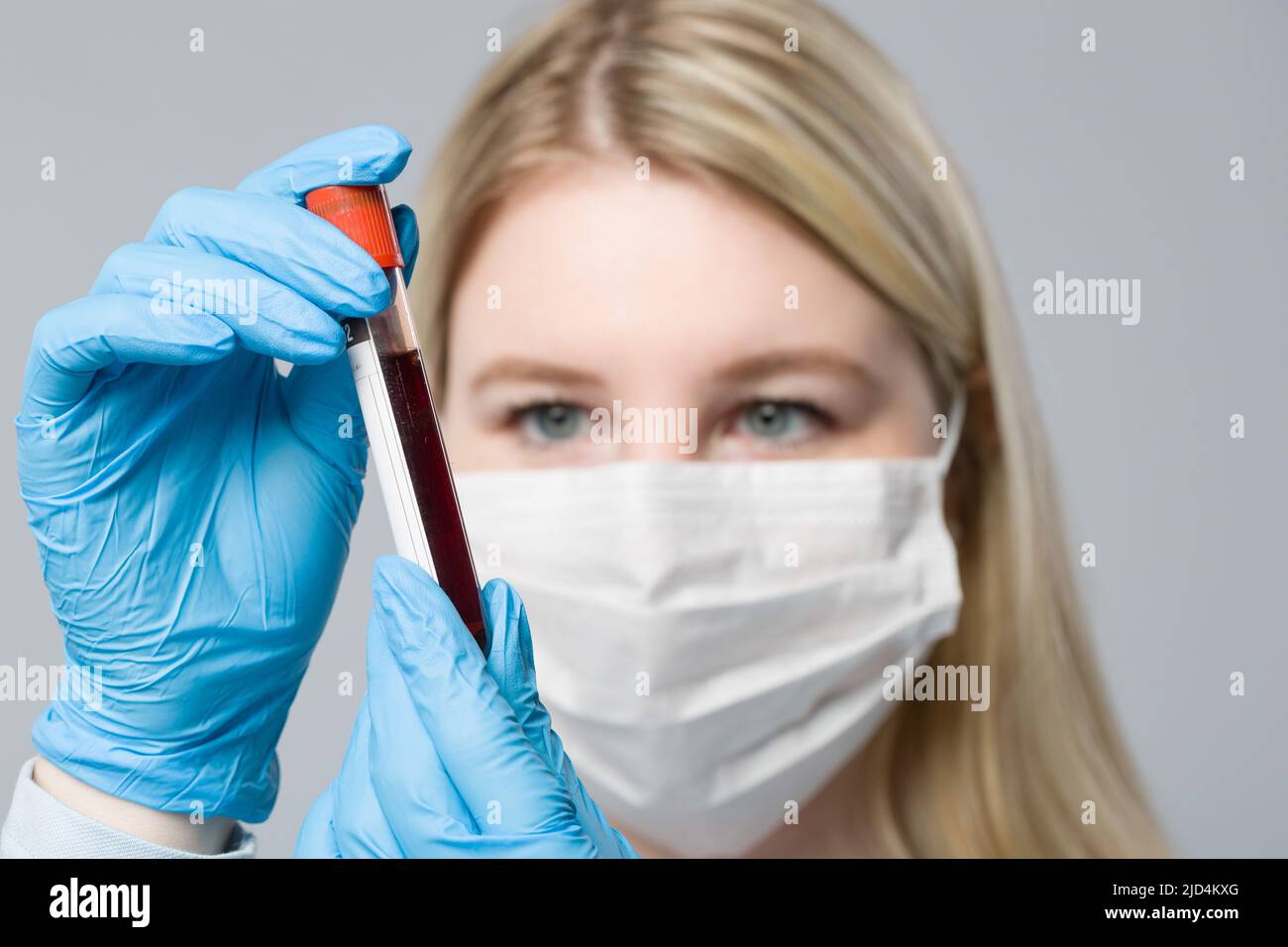 young woman with medical gloves and medical face mask handling a blood ...