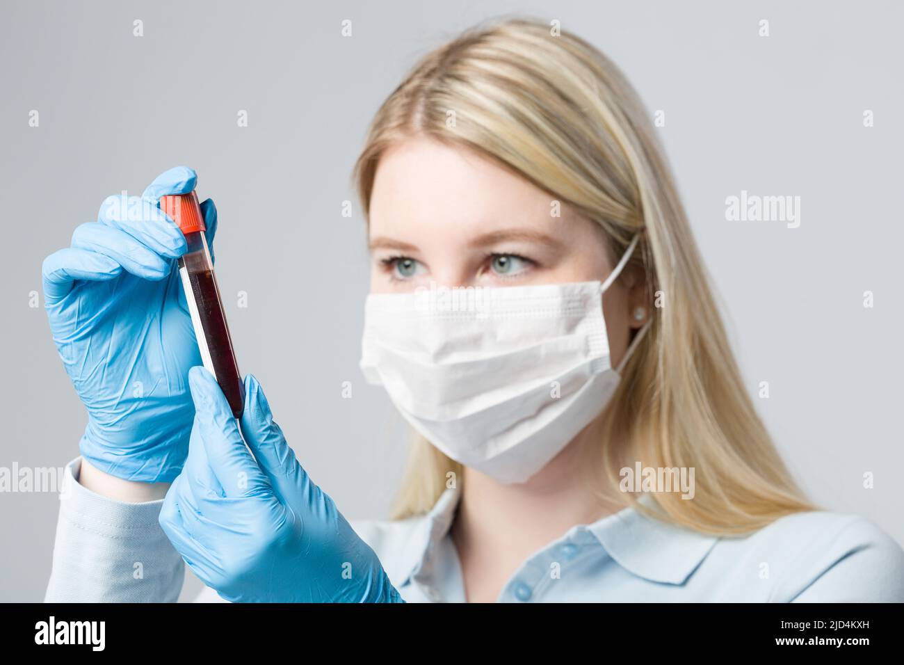 young woman with medical gloves and medical face mask handling a blood ...