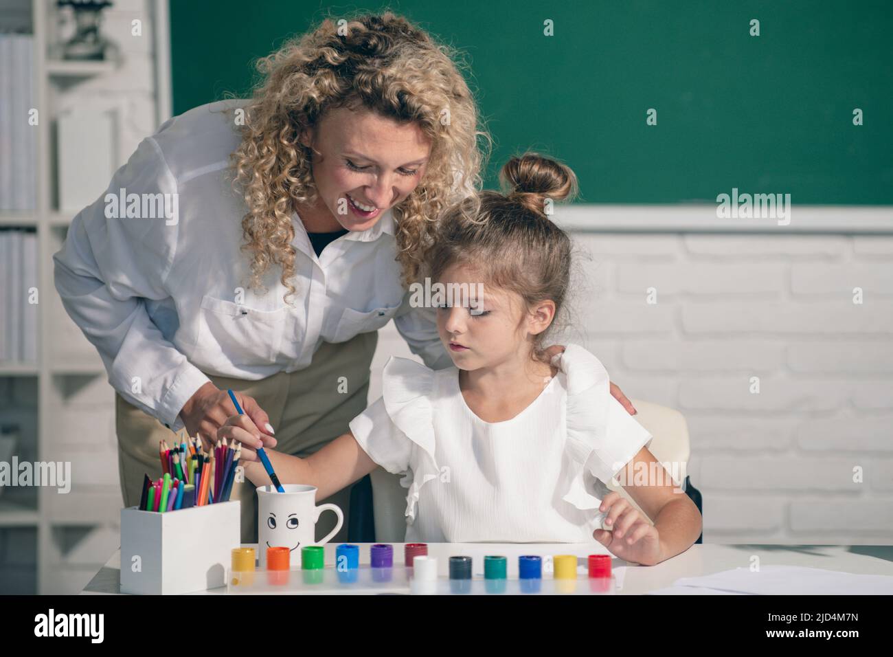 Kid drawing with teacher. Children from elementary school study at draw ...