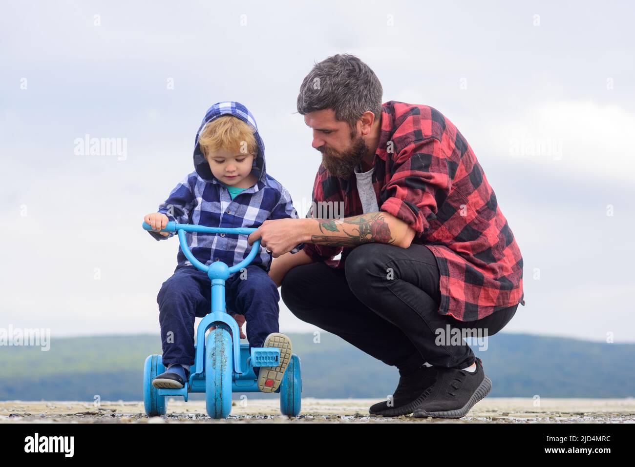 Father and son play with bike outdoor. Father teaches baby son child to ...