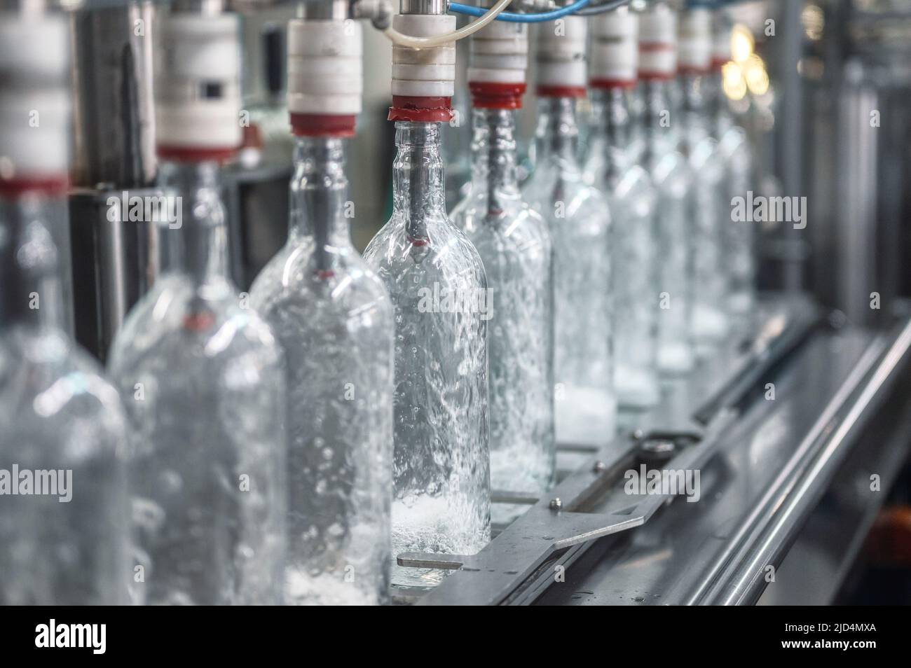 Equipment pours vodka into glass bottles on production line Stock Photo ...