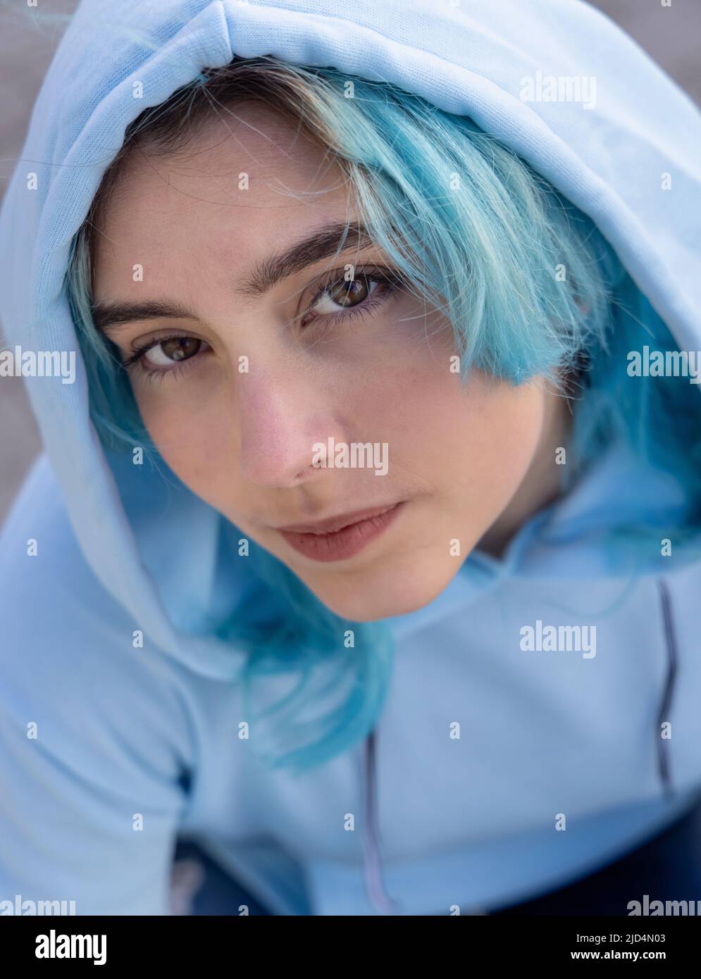 Blue haired Teenage girl in light blue oversize hoodie and looking into ...