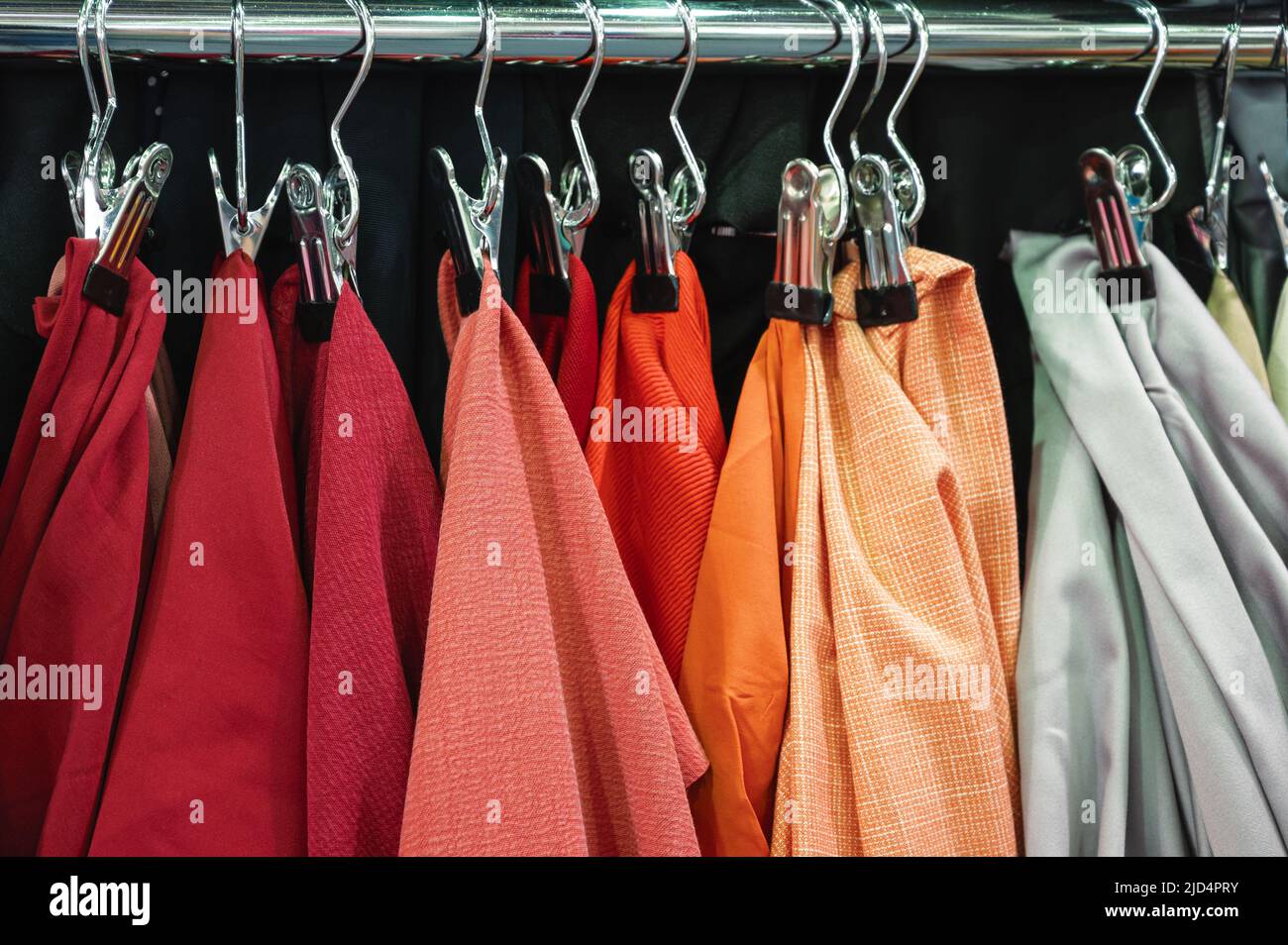 Samples of bright color fabrics hang on metal rack bar Stock Photo - Alamy