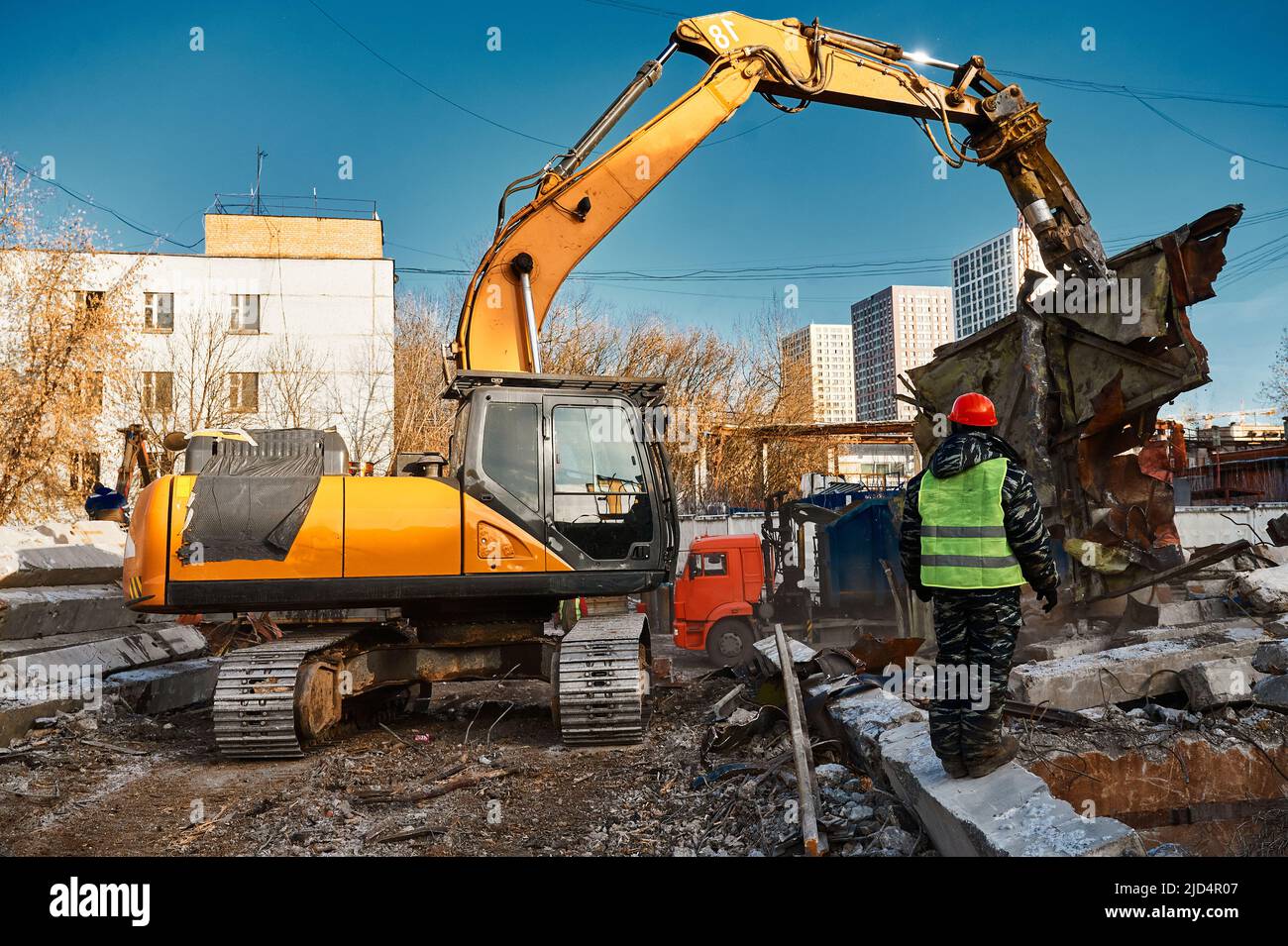 Excavator destroyer removes debris under worker control Stock Photo - Alamy