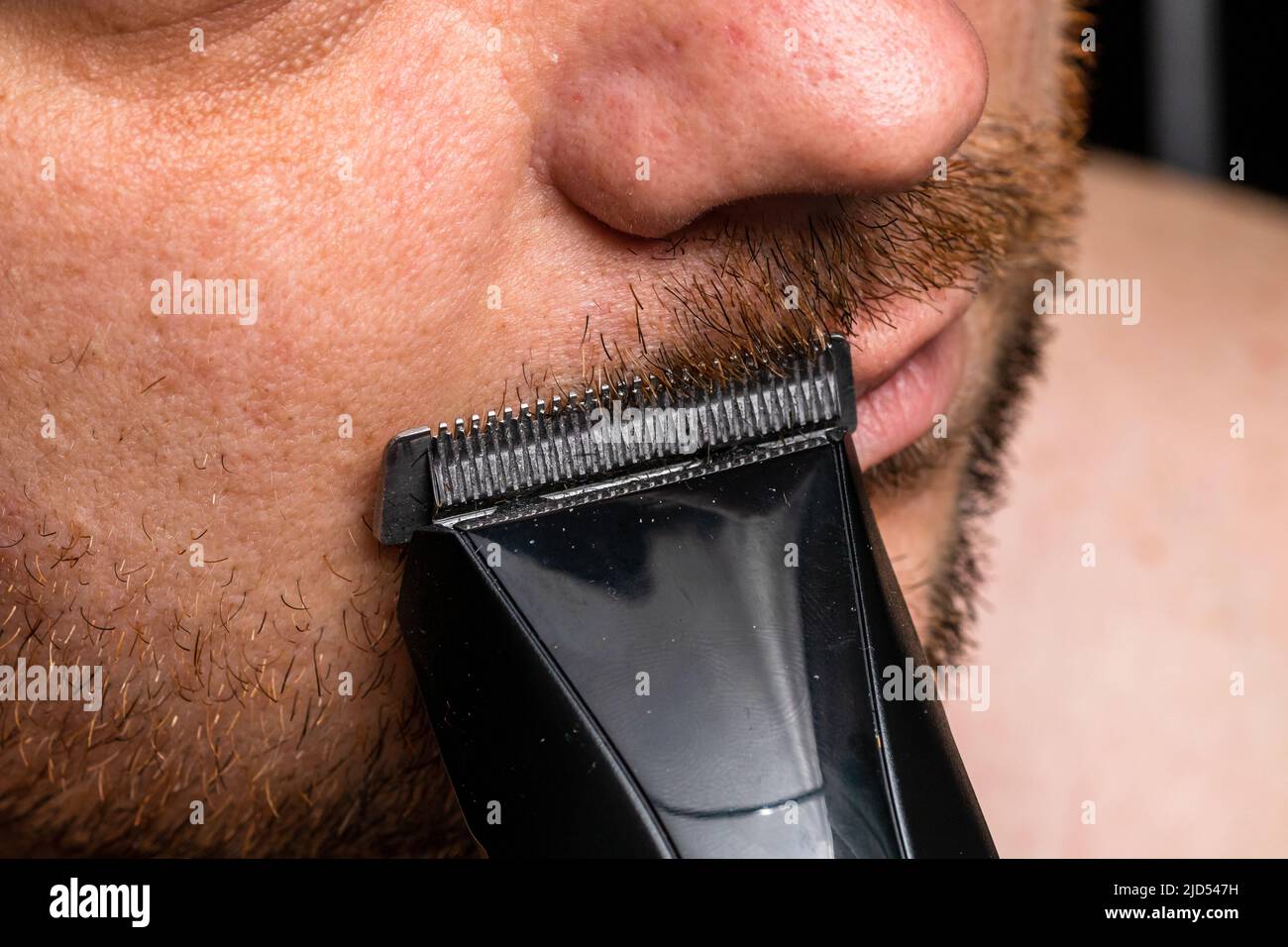 Man shaving or trimming his beard using a hair clipper Stock Photo - Alamy