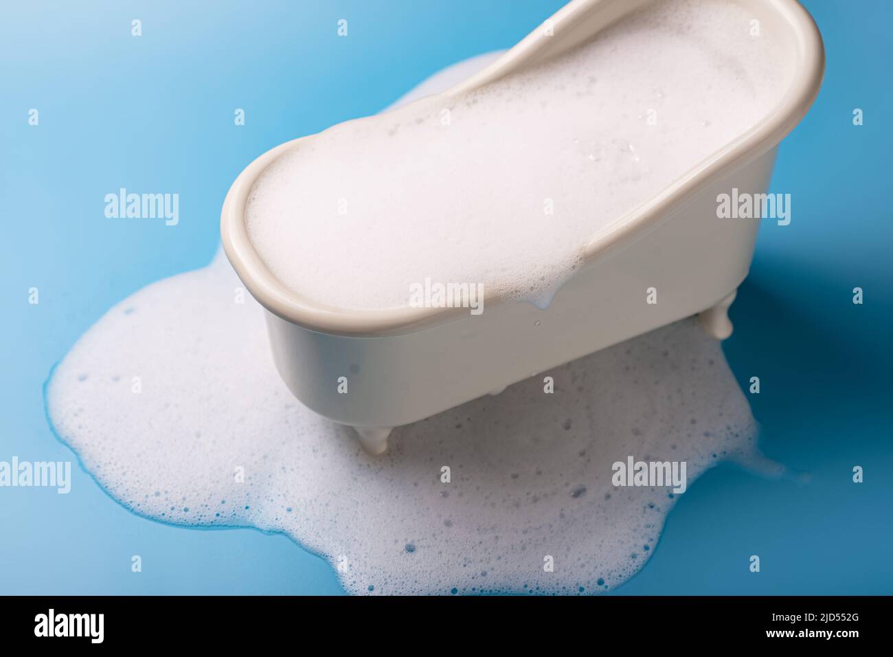 Toy bath with flowing soap foam on a blue background. The concept of ...