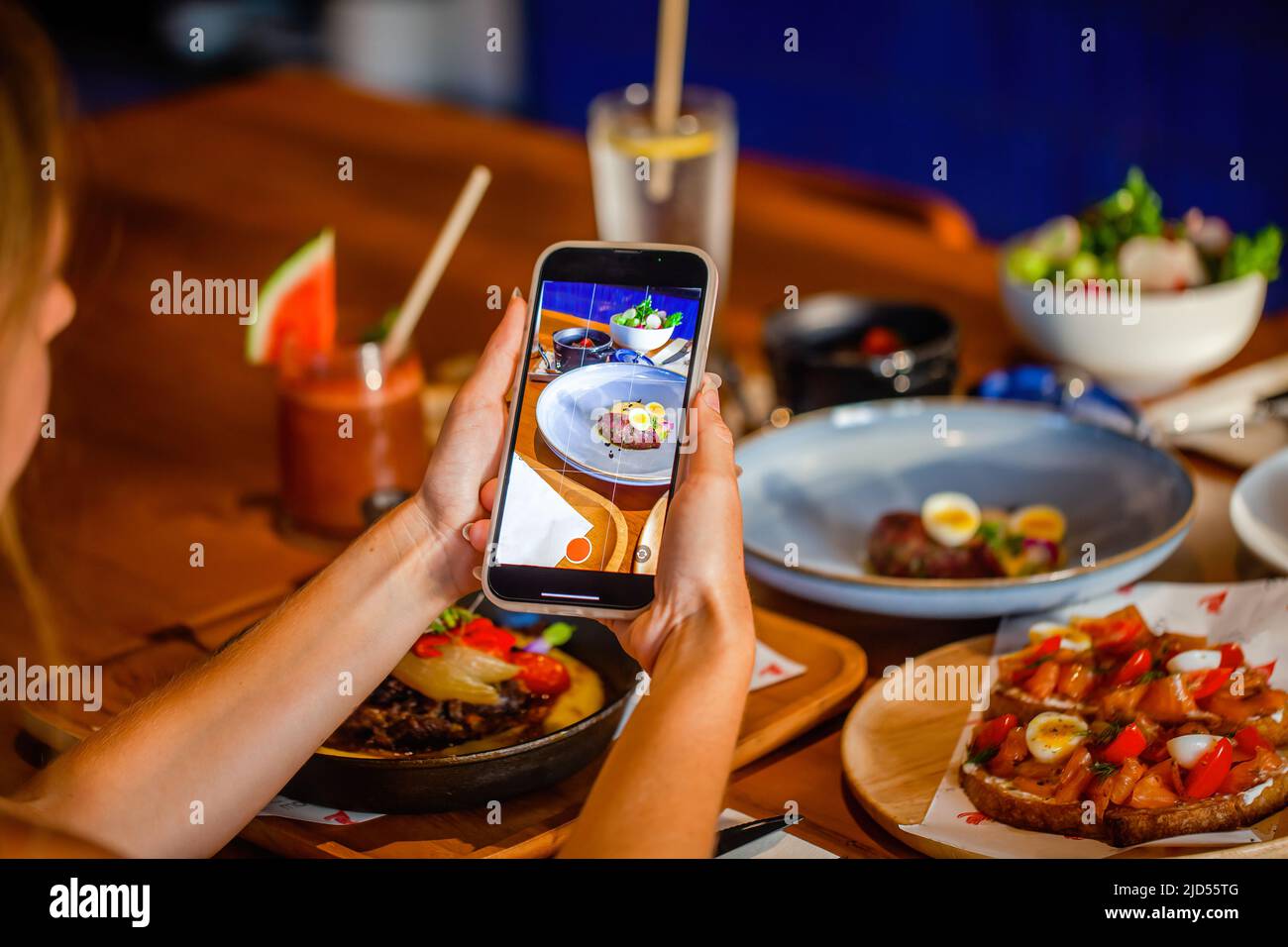 Woman photographing dinner in restaurant through mobile phone at table ...
