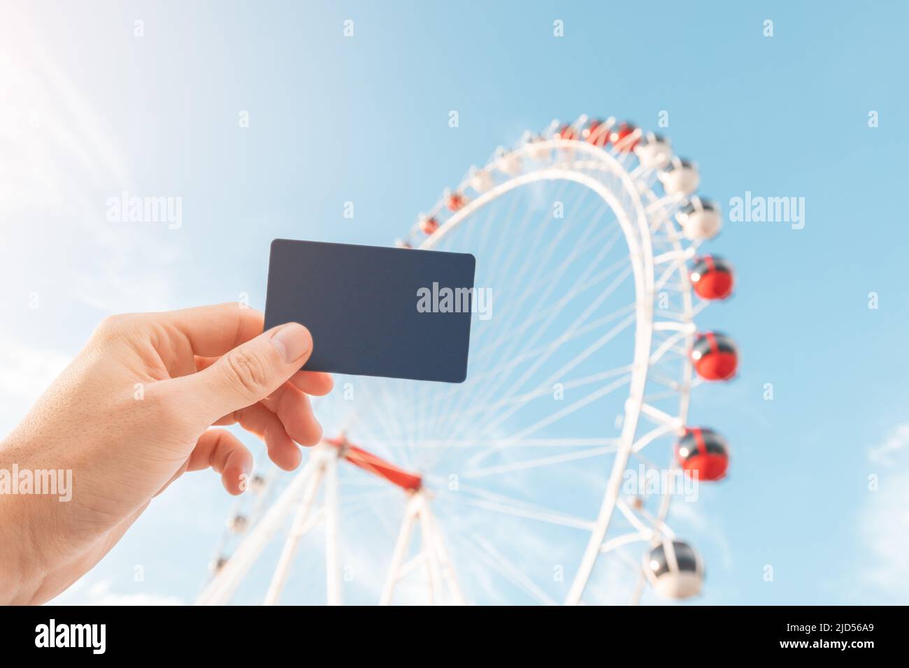 Hand holding white card as entrance ticket or discount with ferris ...