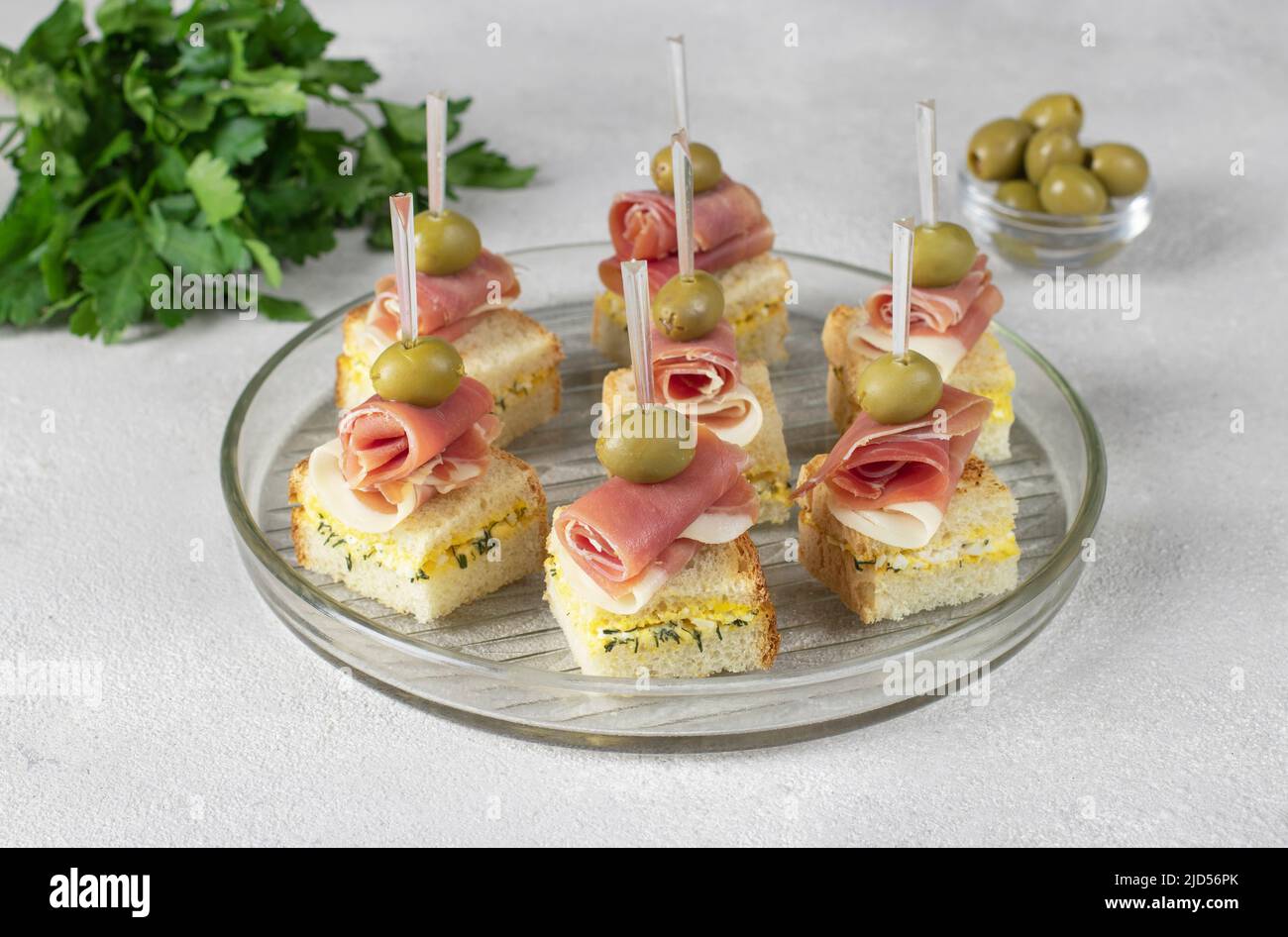 Canape with jamon and olives on toasted white bread with cheese on ...