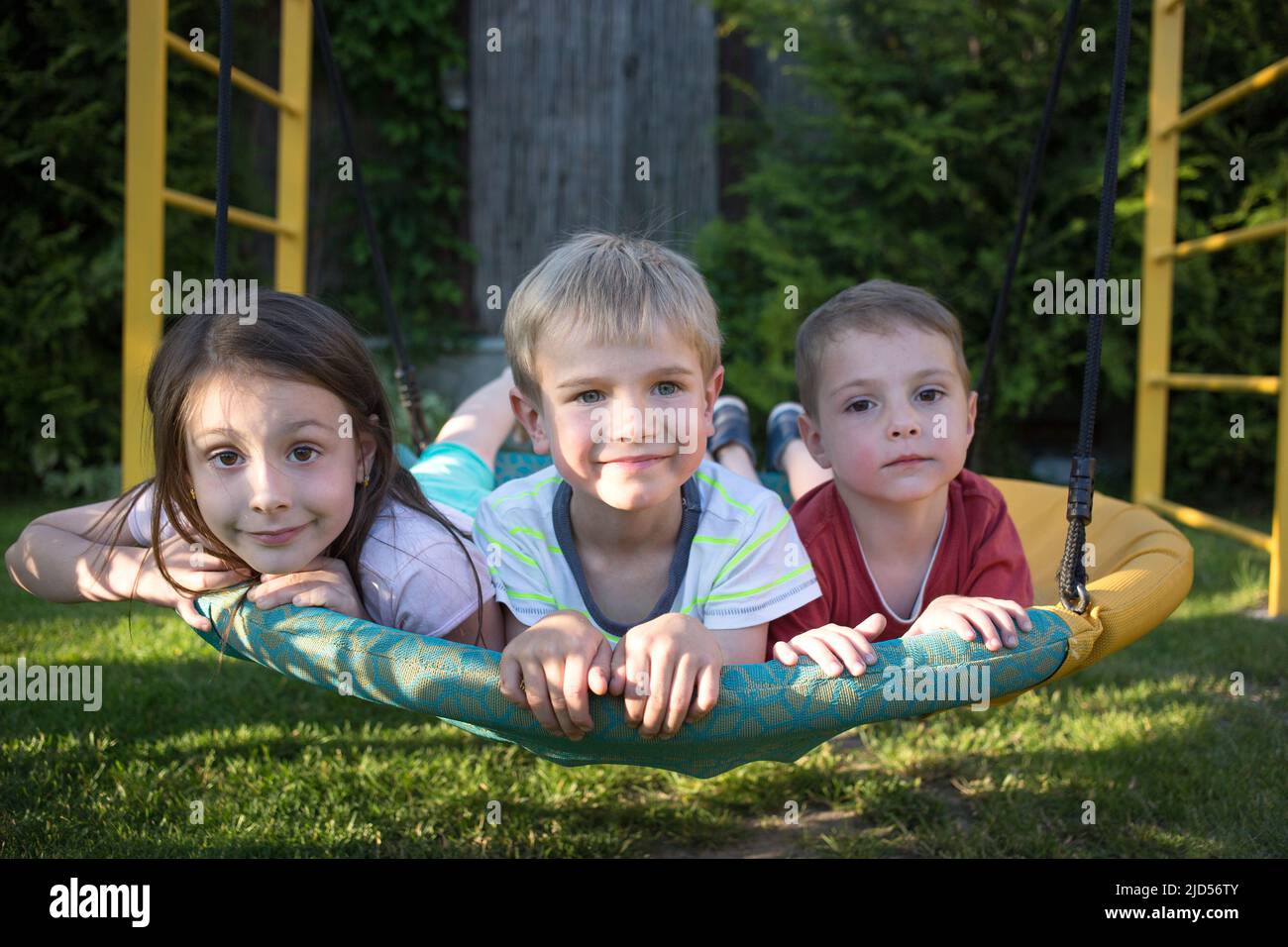 three children, a girl and boys, brothers and sister, swing lying on a ...