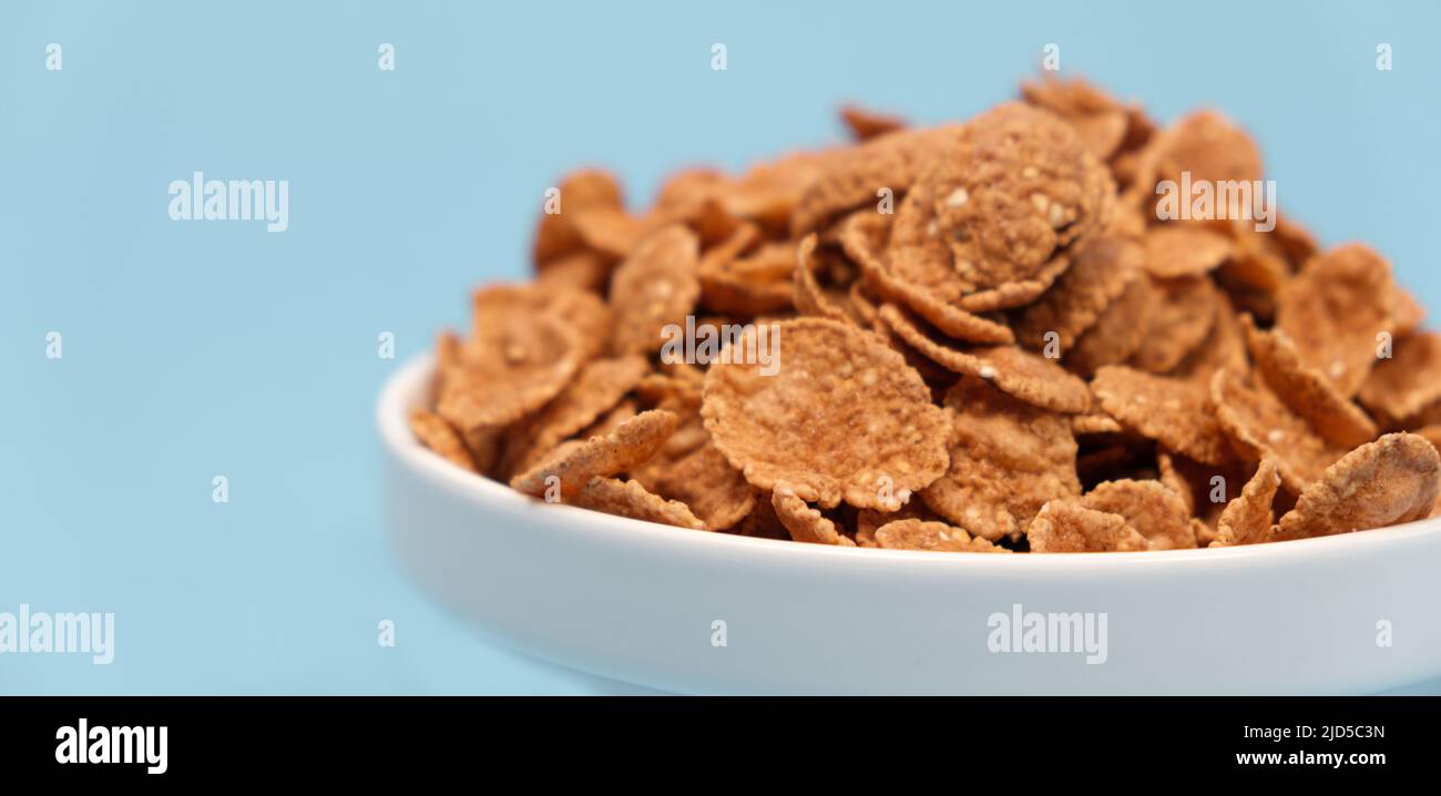 Durum wheat flakes - quick breakfast cereal on a plate on a light blue ...