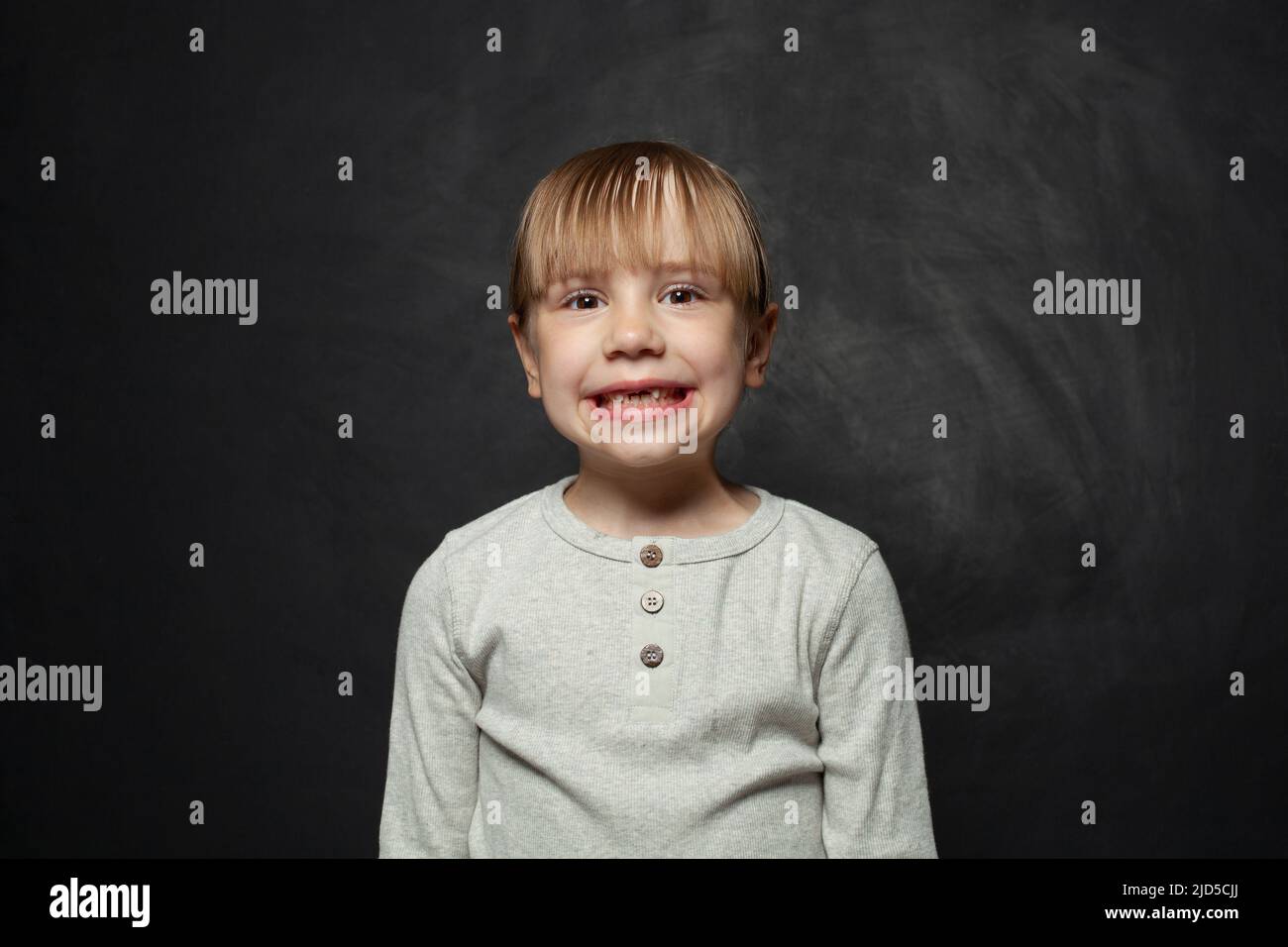 Funny young girl kid laughing and grimacing on black blackboard ...