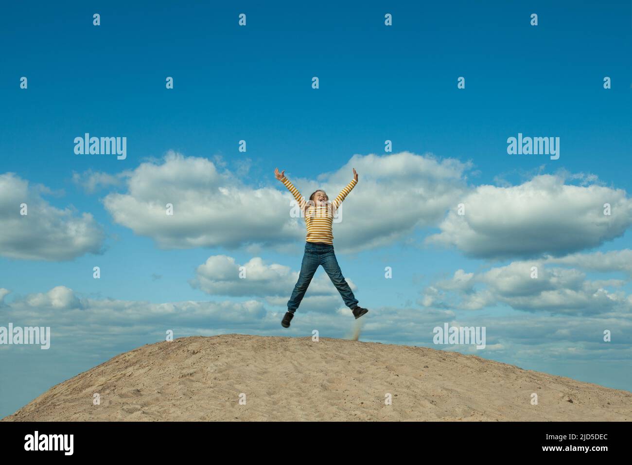 Happy child jumping against sky clouds background outdoors. Smiling kid ...