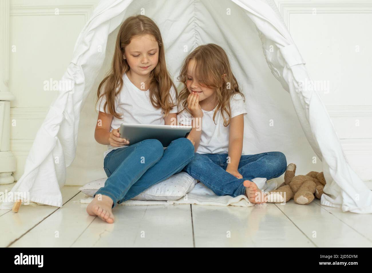 Happy children using a tablet computer in living room at home Stock ...