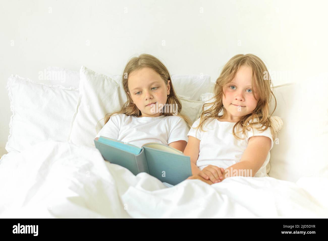 Little children reading book in bedroom at home Stock Photo - Alamy
