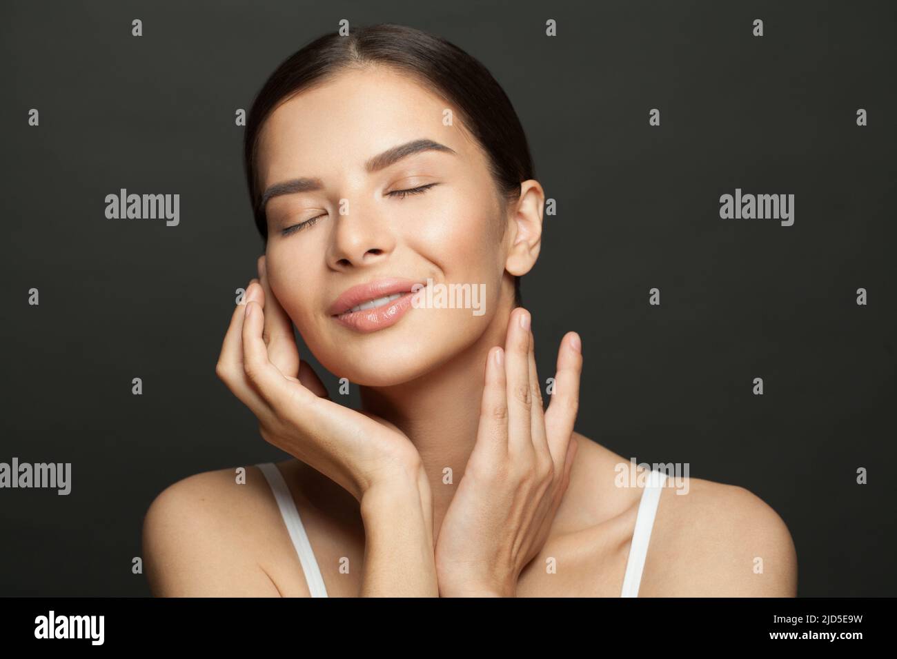 Young brunette female touching her neck, white background Stock Photo ...