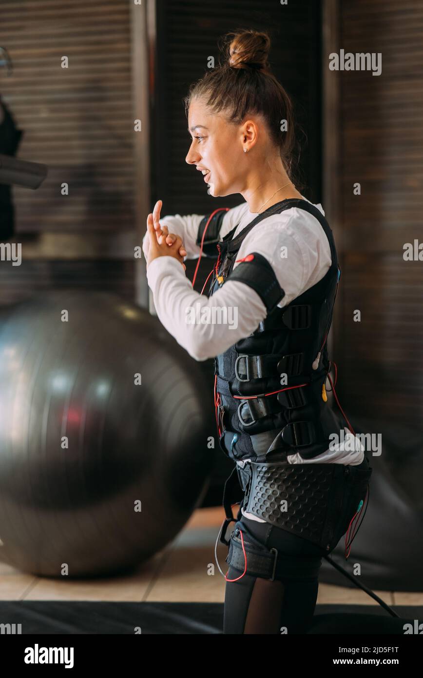 EMS training. Girl doing exercises in a suit with cables Stock Photo ...