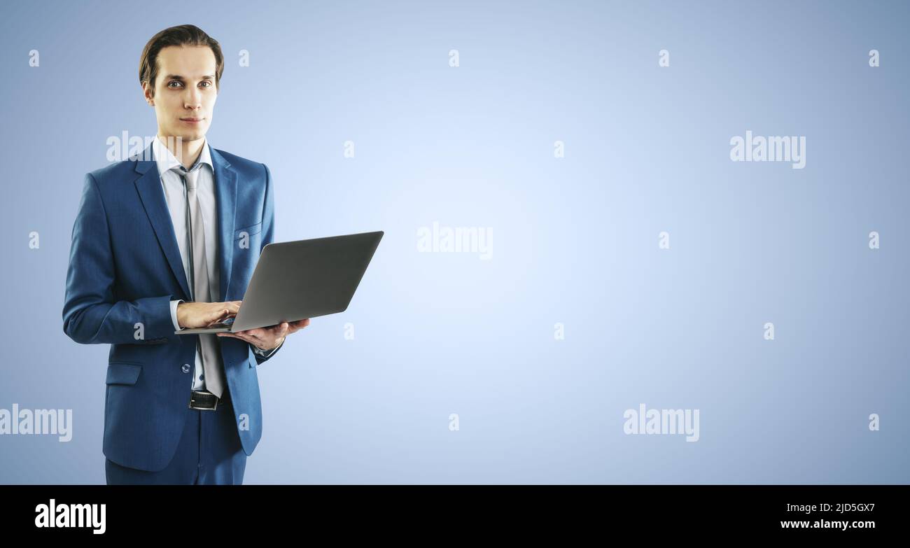 Young businessman in blue suit working with modern laptop, isolated on ...