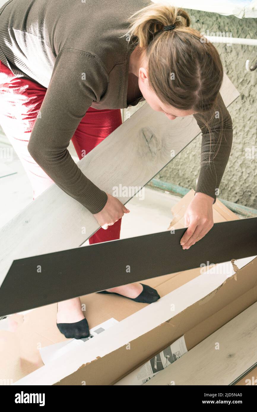 Woman pulls out of the box one board of quartz vinyl, repair work to ...
