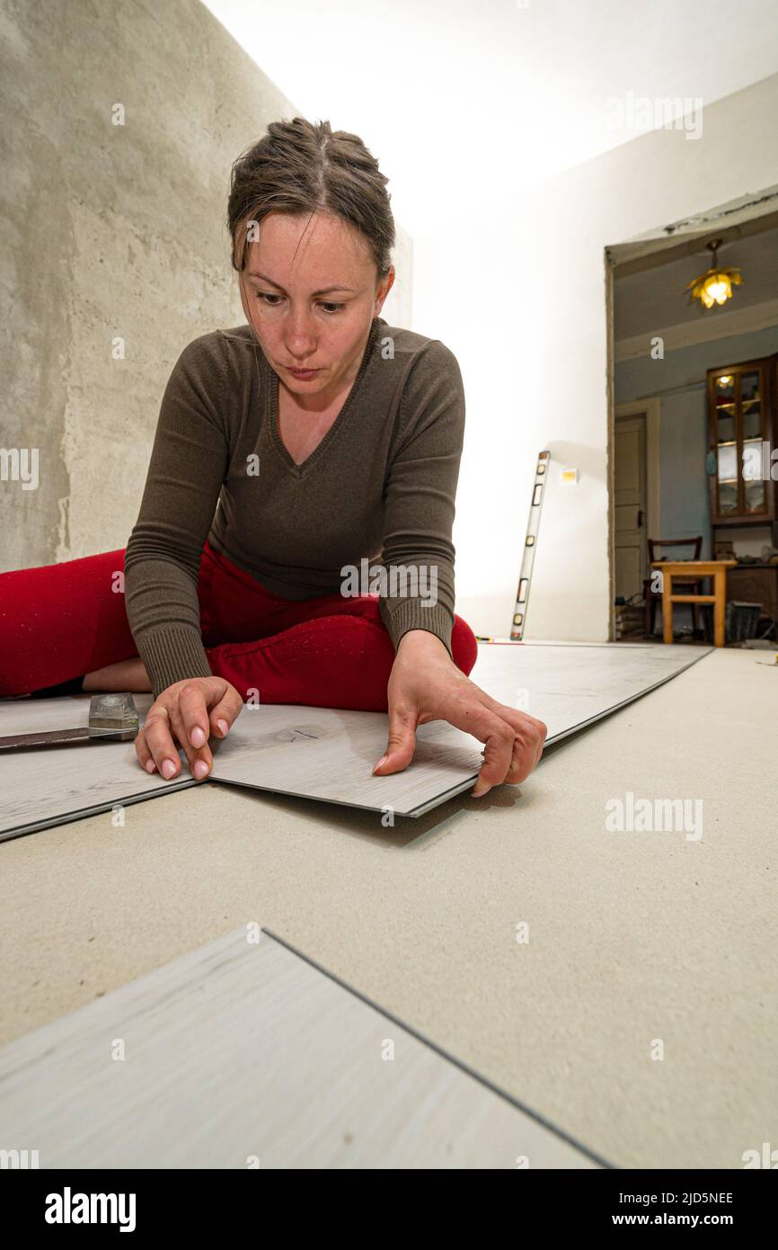 Installing a quartz vinyl floor, a woman performs installation work ...