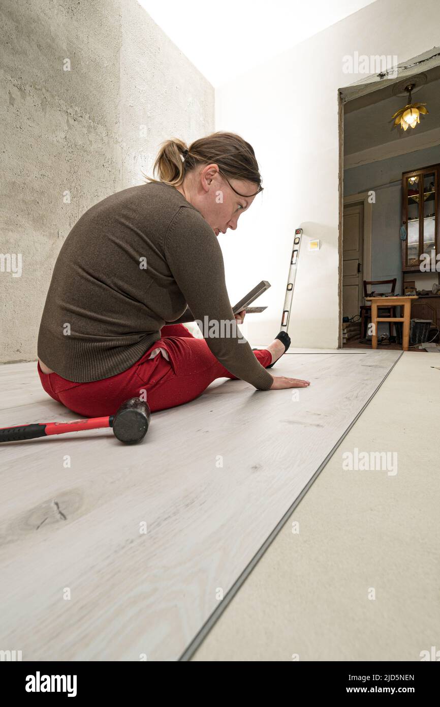 Installing a quartz vinyl floor, a woman performs installation work ...