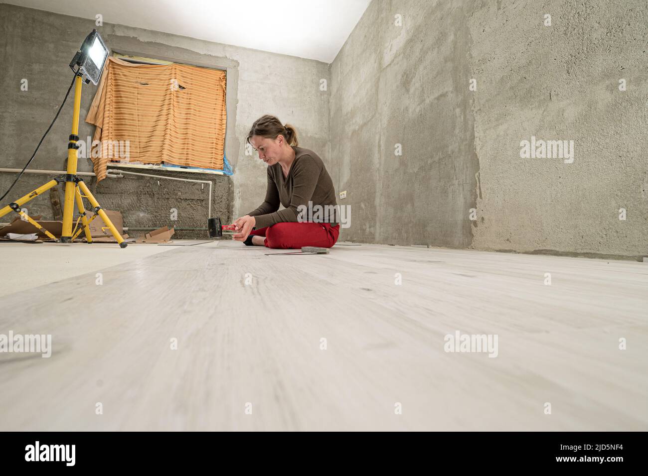 Woman installs quartz vinyl flooring at home, exhausted woman from work ...