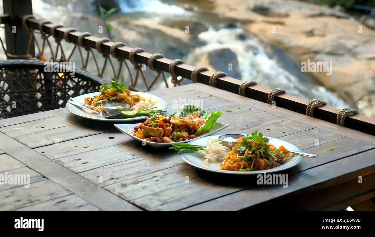 Traditional thai food in outdoor cafe with nature waterfall background ...