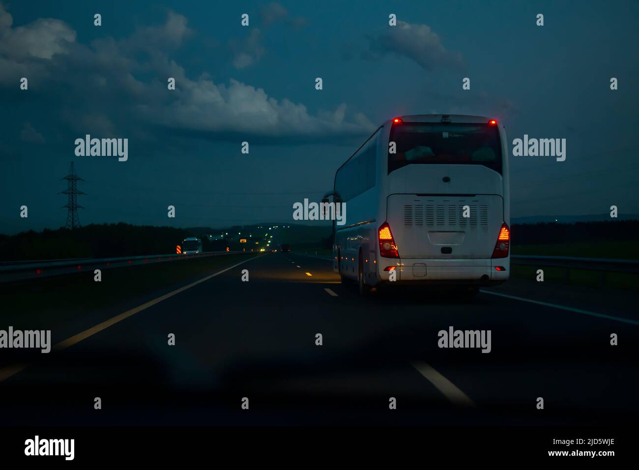 a view of a passenger white bus traveling along the highway on a night ...