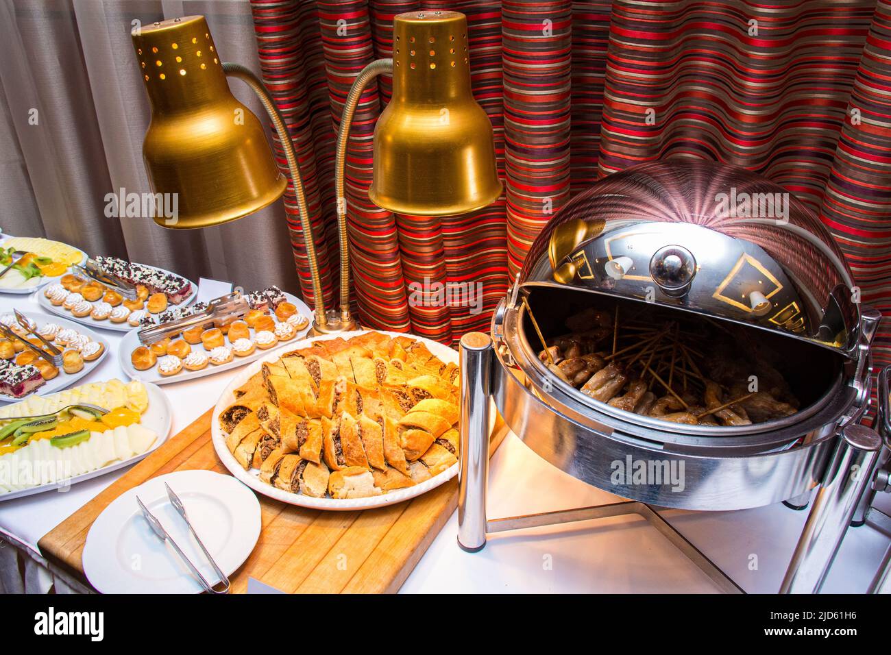 Buffet line tables, catering serving. A metal marmite is a heated dish ...