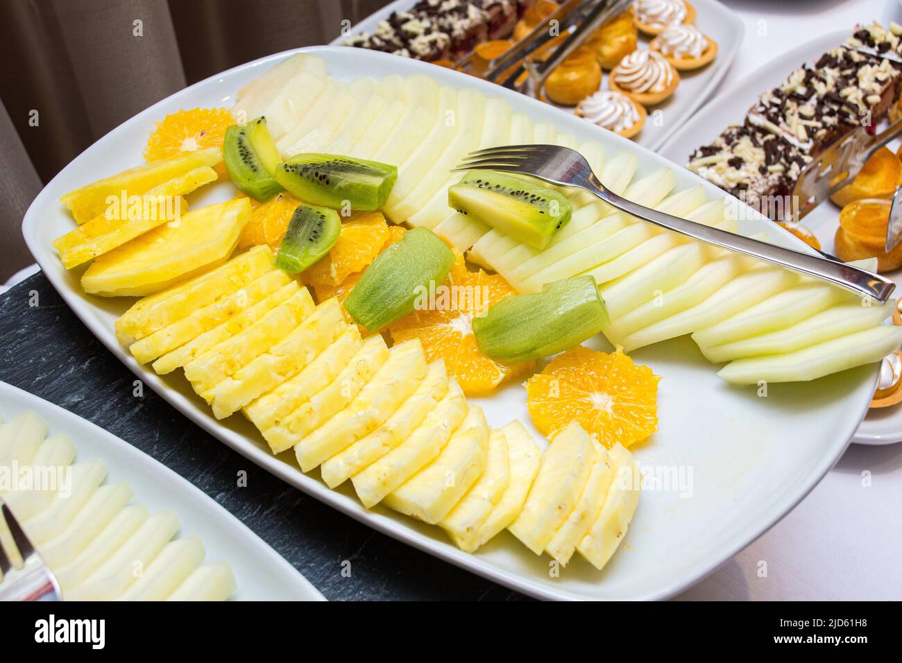 Plate with sliced fruits: pineapple slices, kiwi, orange. Catering ...