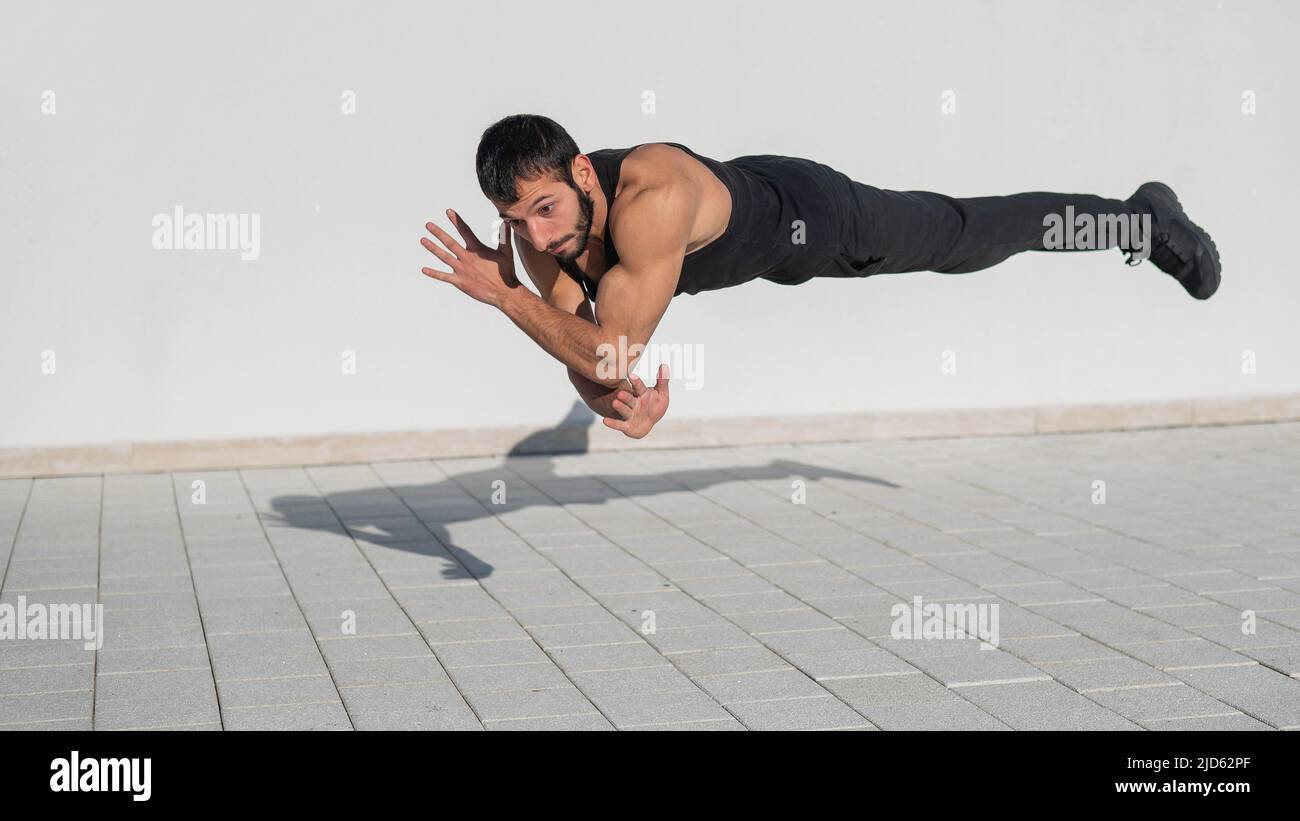 A man in black sportswear jumps while doing push-ups outdoors Stock ...