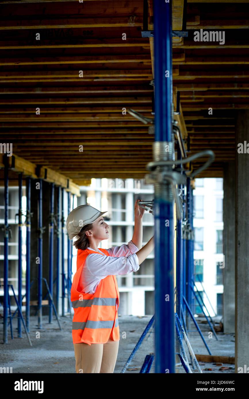 Confident Female builder checks fastenings on a monolithic structure ...