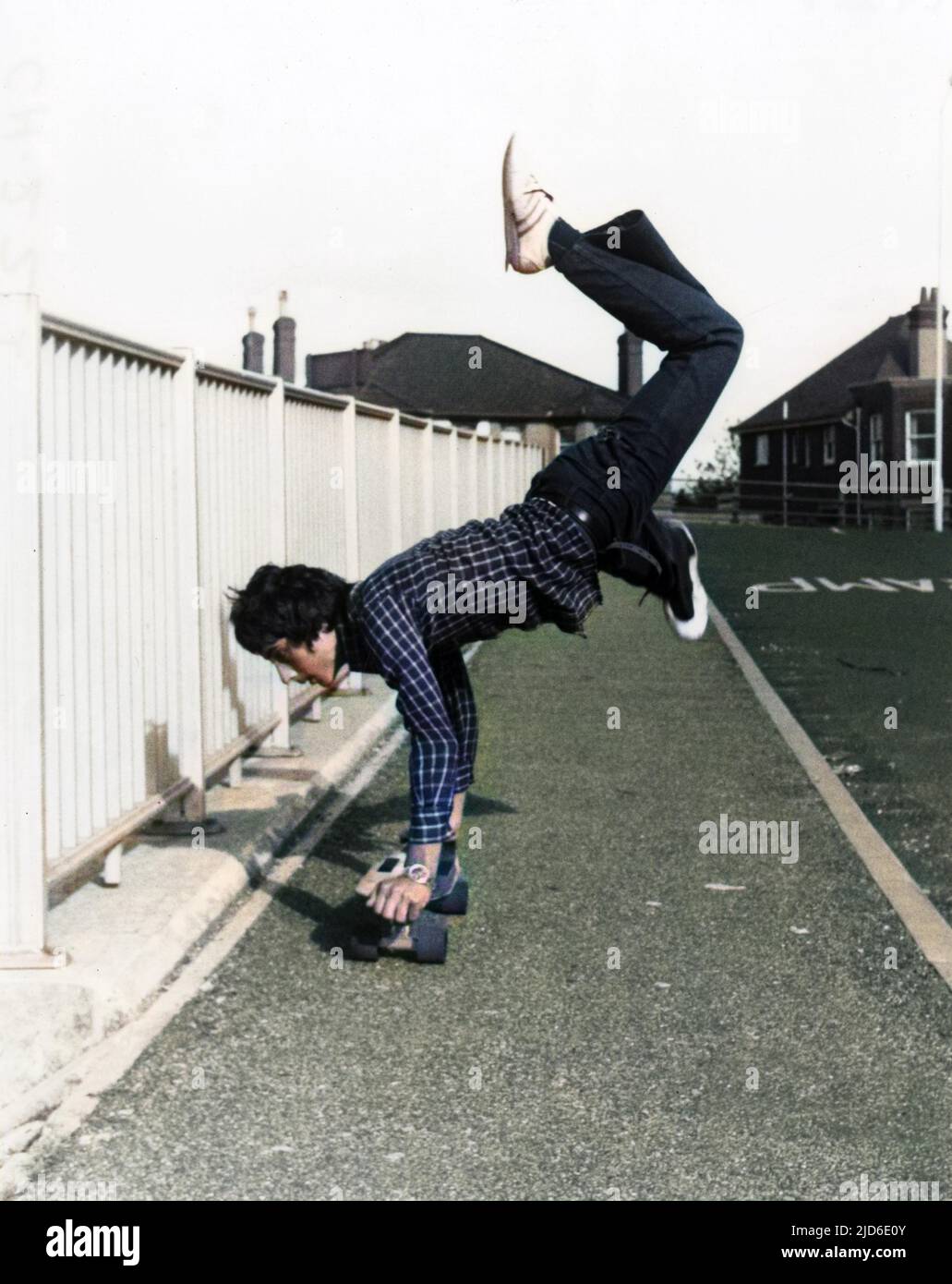 A young man performs a handstand trick on his skateboard Colourised ...