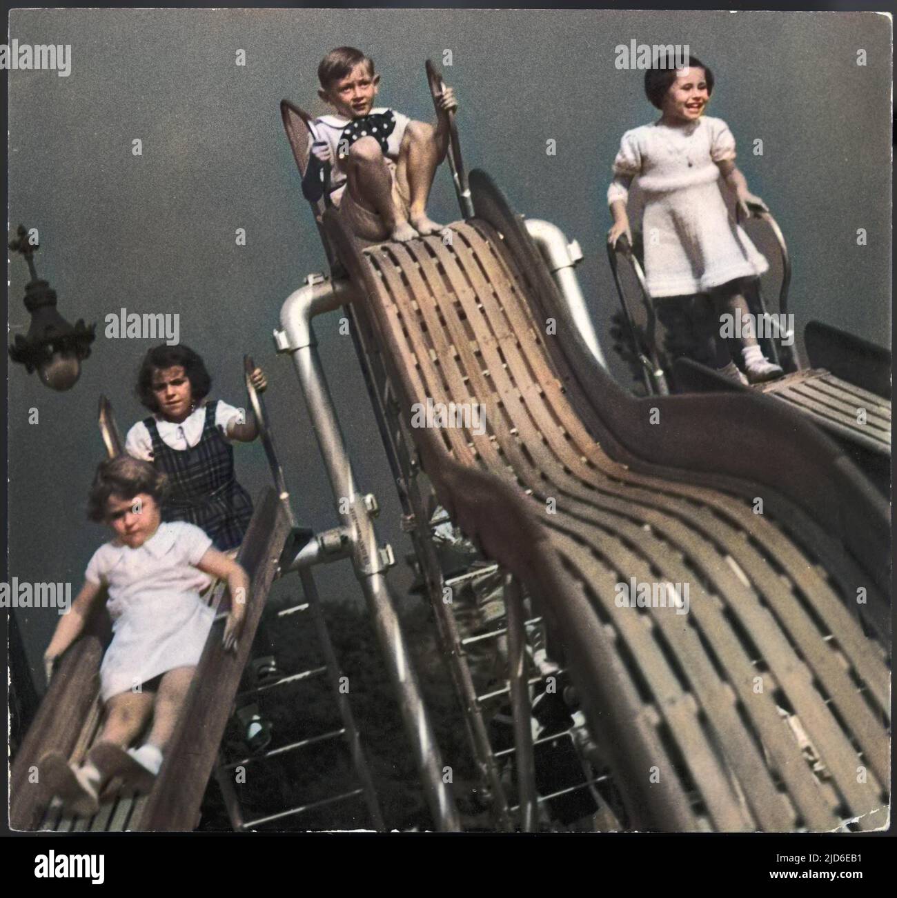 Boys and girls play on the slides at a playground Colourised version of ...