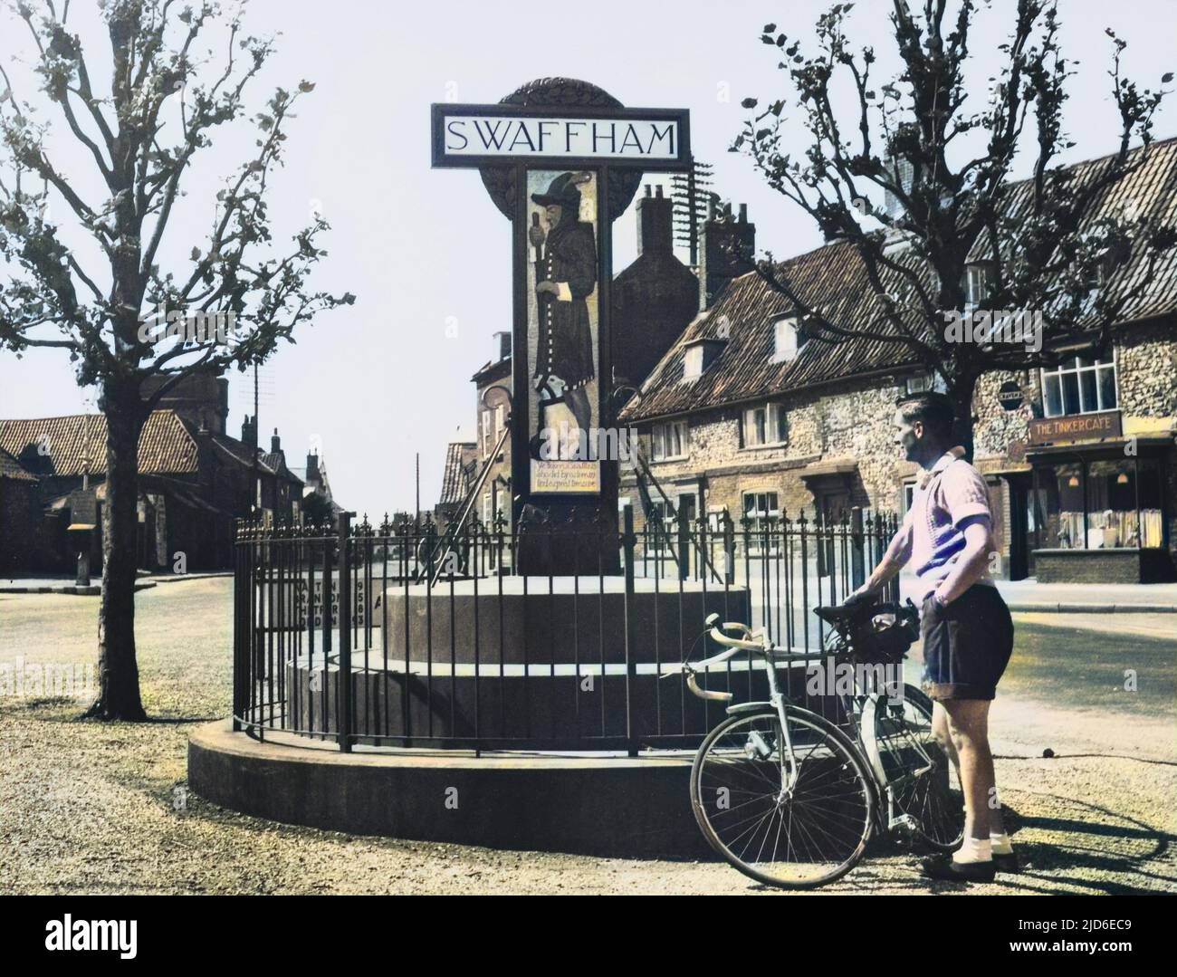 A lone cyclist pauses to study the elaborate town sign of Swaffham ...
