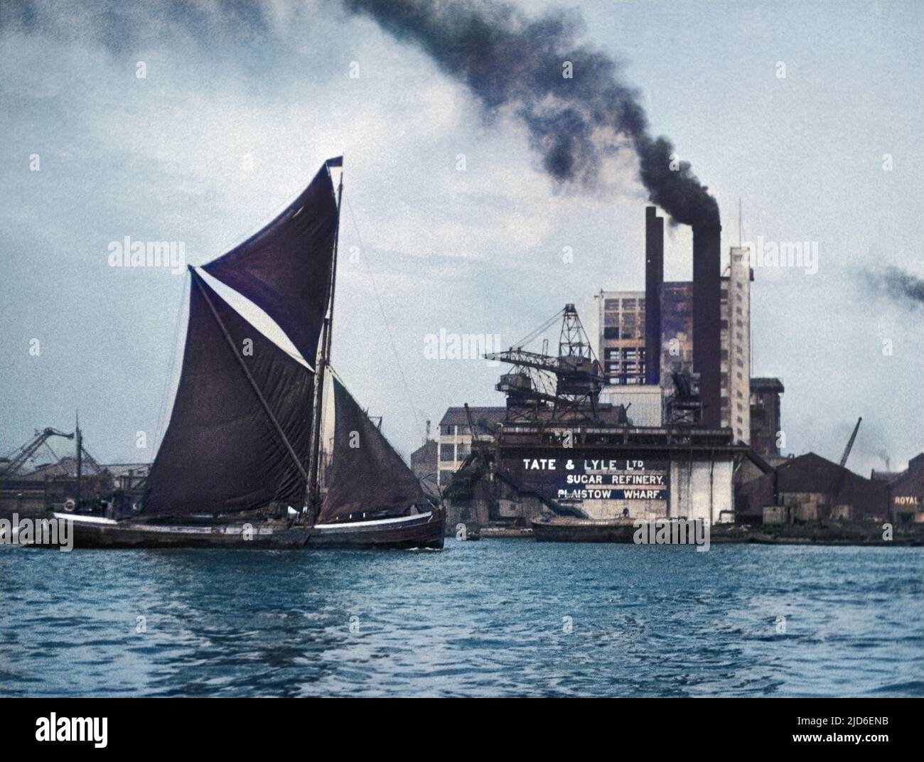 A coastal barge sailing by the famous Tate and Lyle sugar refinery ...