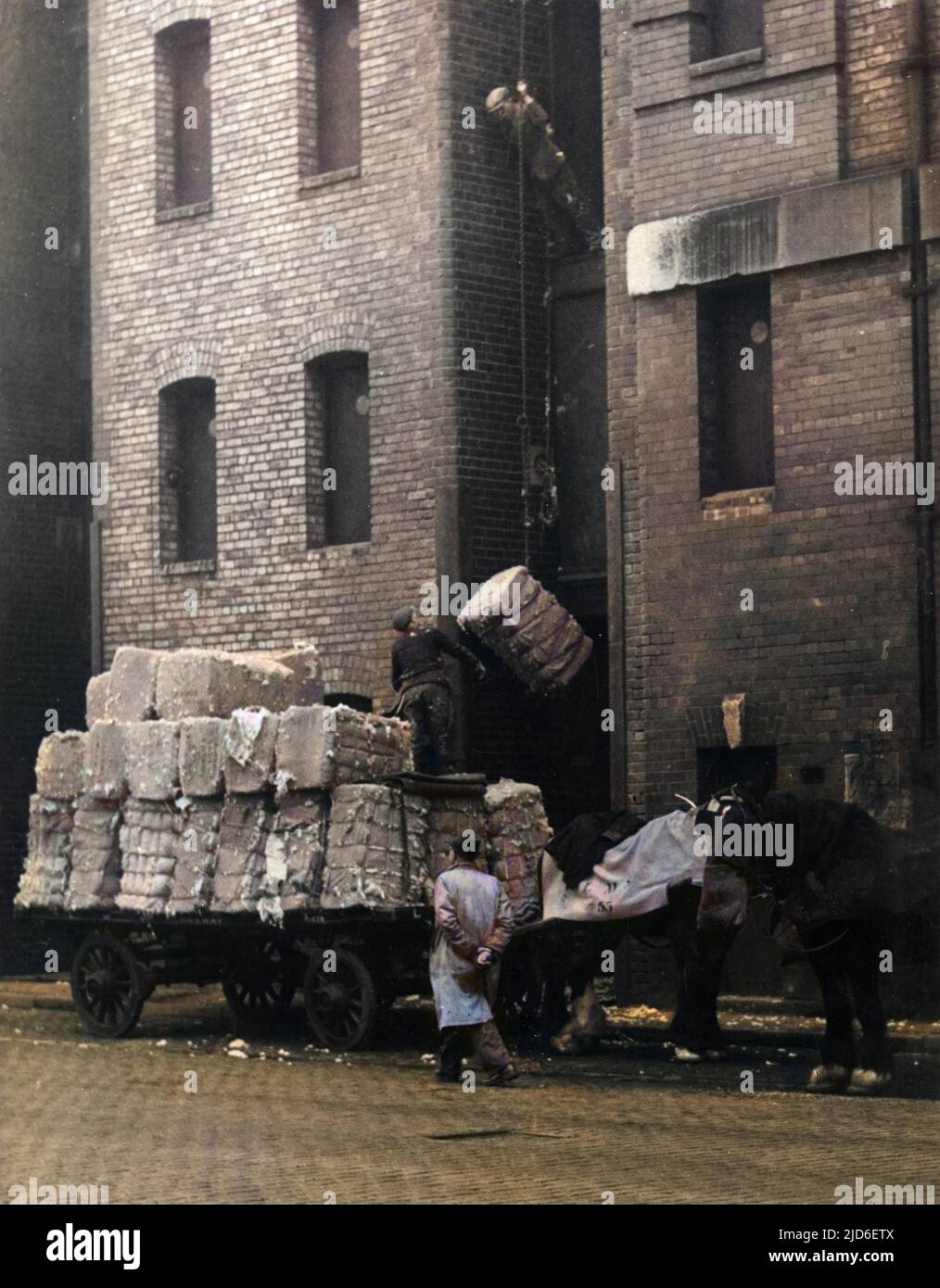 Men loading a wagon with bales of cotton from a warehouse in Manchester ...
