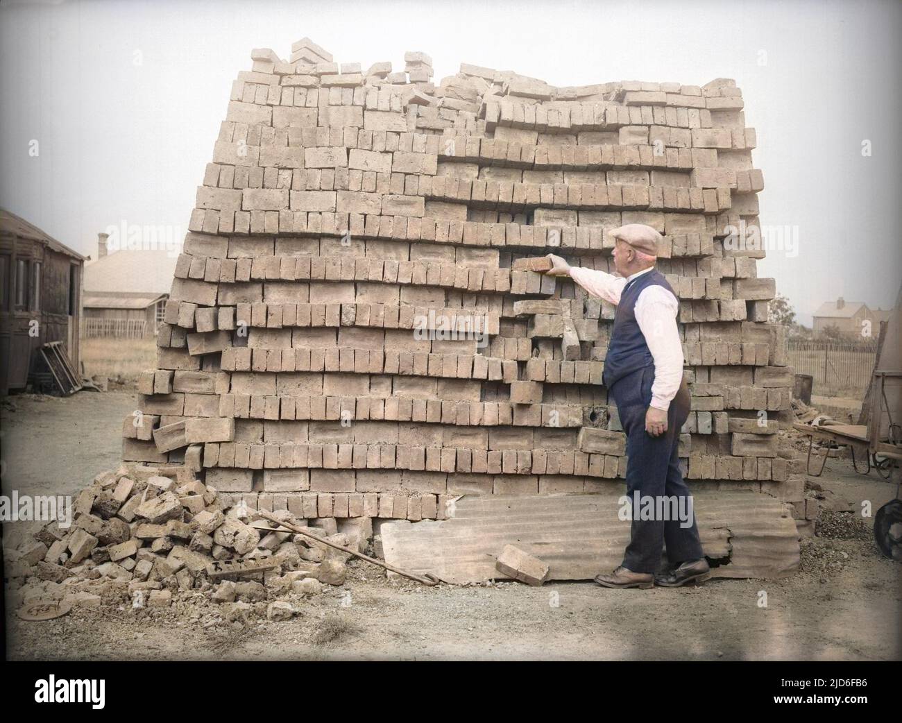 An old man stacking bricks in an industrial brick yard. Colourised ...