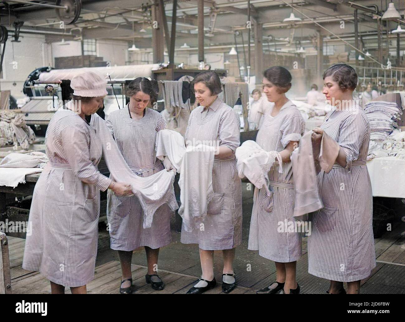 The supervisor of a public laundry demonstrates how to fold clothes ...