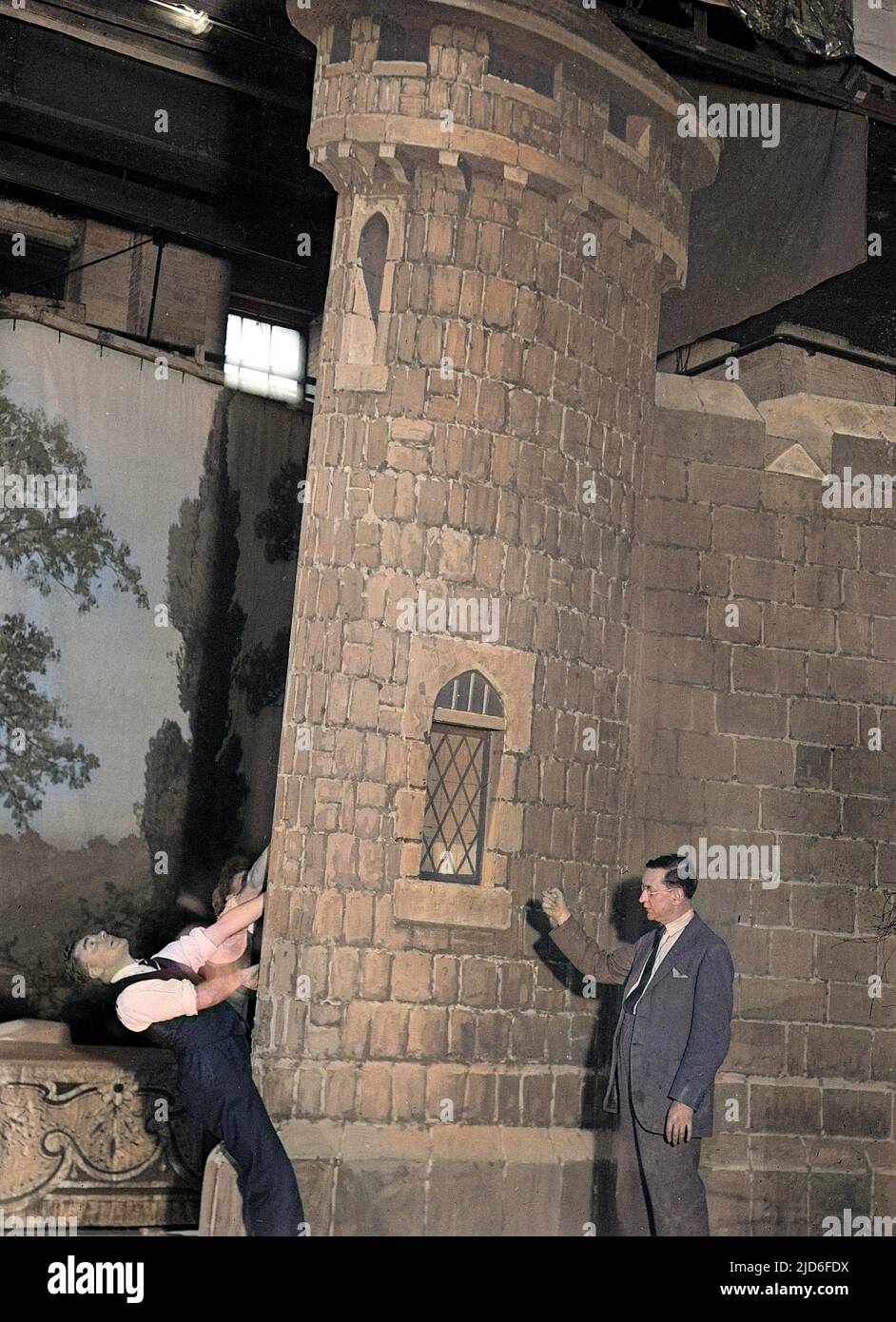 A theatre production worker hauling up a stage set of a castle, under ...