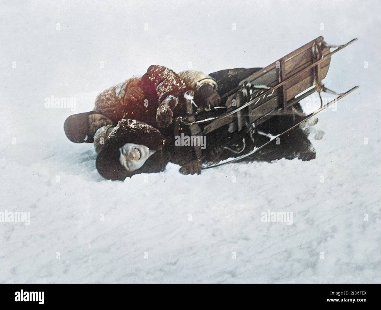 Two young people in fur hats and coat, curled up with laughter after a ...