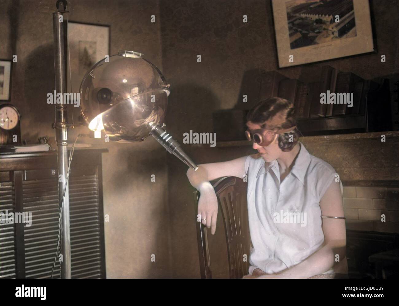 A young woman wearing goggles is subjected to radiation therapy, using ...