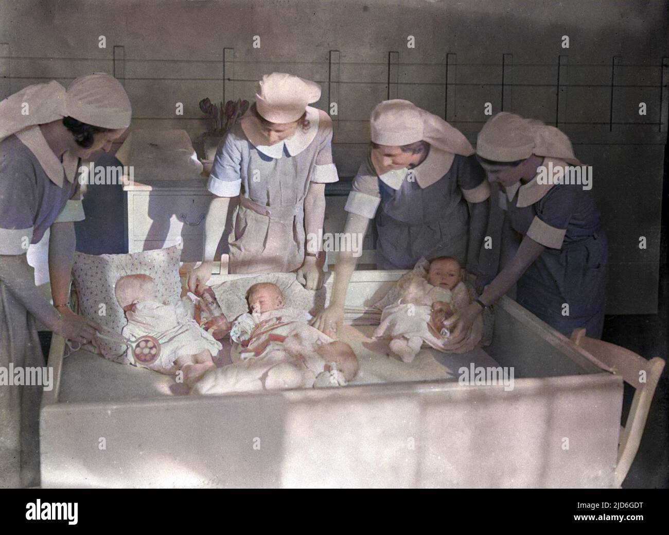 A group of nurses laying down three babies for sunlight treatment ...